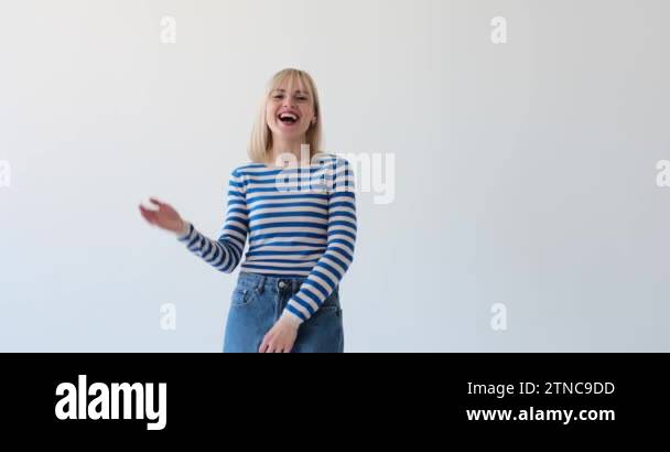 A friendly woman is seen on a clean white backdrop, laughing heartily ...