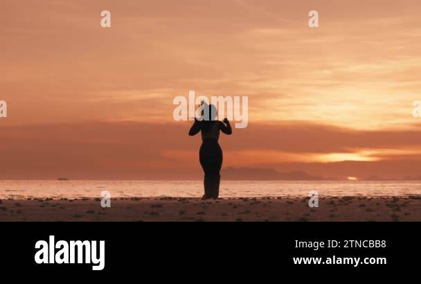 Back view woman winner at sunset jumping on golden sunset background ...