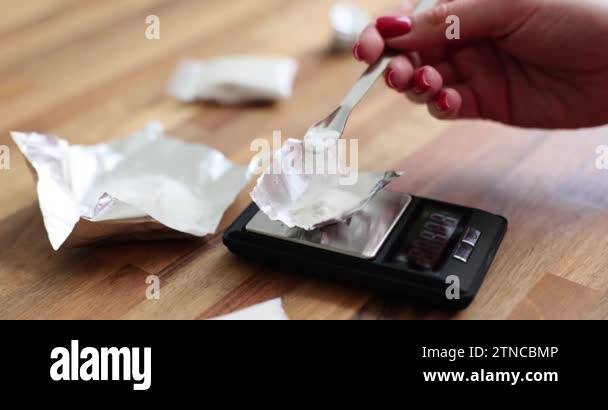 Female hands weigh white powdery substance on sheet of foil using scale ...