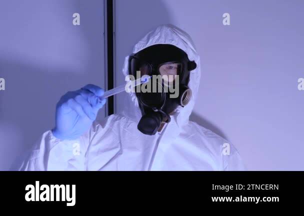 A worker in chemical protection examines a radioactive stone, a man in ...