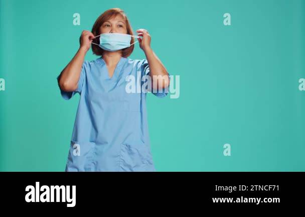 Nurse putting on medical face mask before starting hospital work shift ...