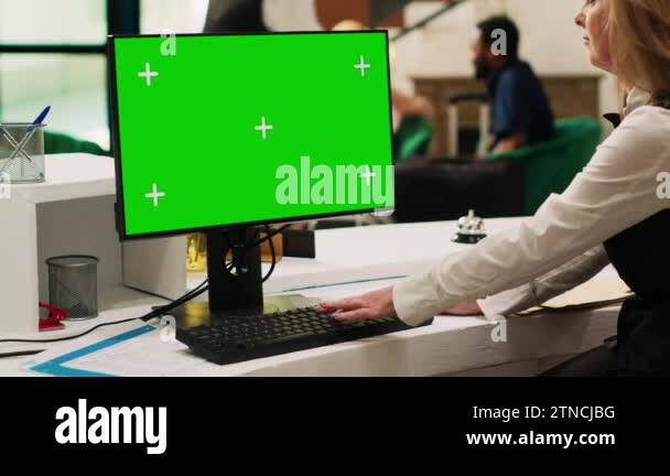 Receptionist using greenscreen pc at front desk lobby, looking at ...