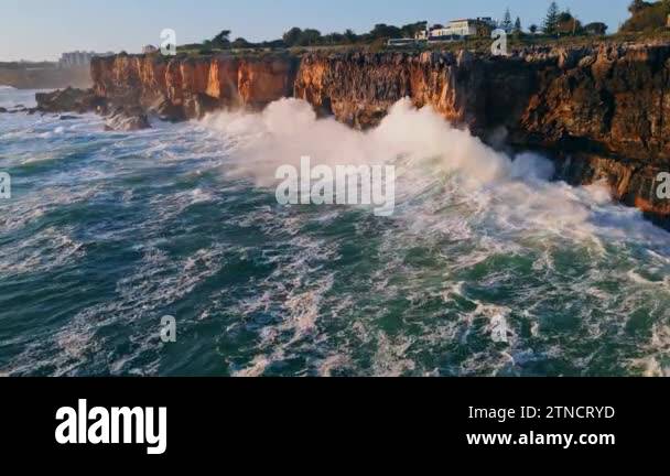 Powerful ocean water crashing on high rocky seashore with huge splashes ...