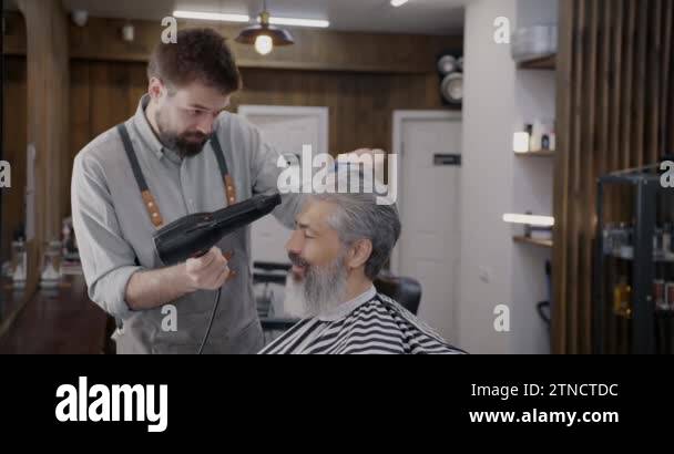 Professional barber brushing hair and using dryer caring for mature ...