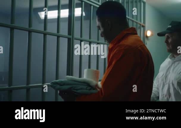 Warden brings guilty prisoner in jail cell and takes off handcuffs ...