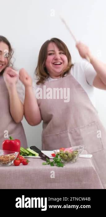 2 women dancing while preparing tasty and healthy food vegetarian food ...