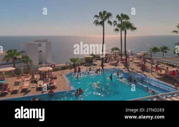 Beautiful top view of RIU hotel pool with people swimming on backdrop ...