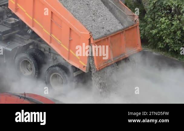 Truck dumping sand and gravel mix on the road. Machine pour out stones ...