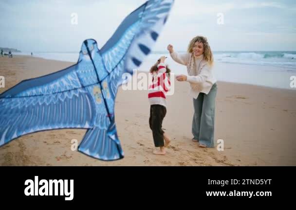 Family playing kite together on windy seaside. Happy mother spending ...
