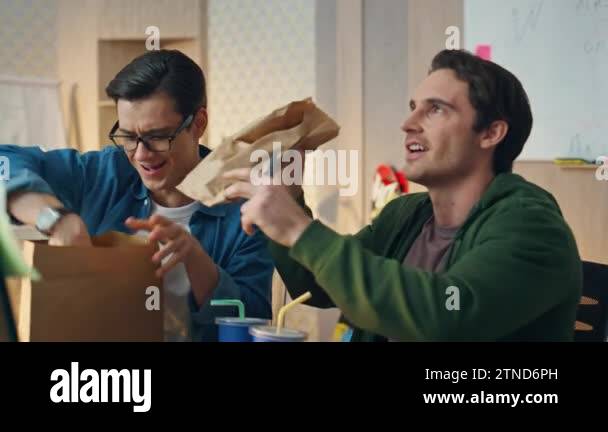 Happy man proposing sandwich to colleague at office closeup. Two guys ...