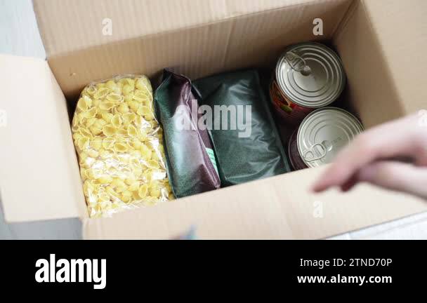 A man collects a box of food to donate to the poor during a pandemic or ...