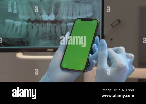 Closeup dentist hands sterile glove hold green screen cellphone at ...