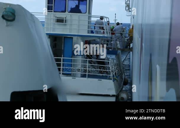 People are loading supplies from the cruise ship on the smaller ship ...