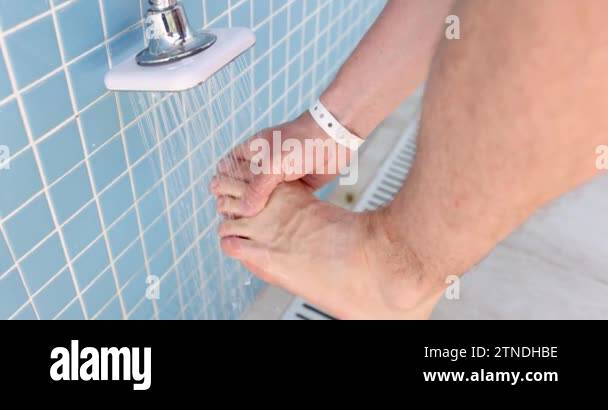 Man washing his feet from sand under shower on sea beach closeup 4k ...
