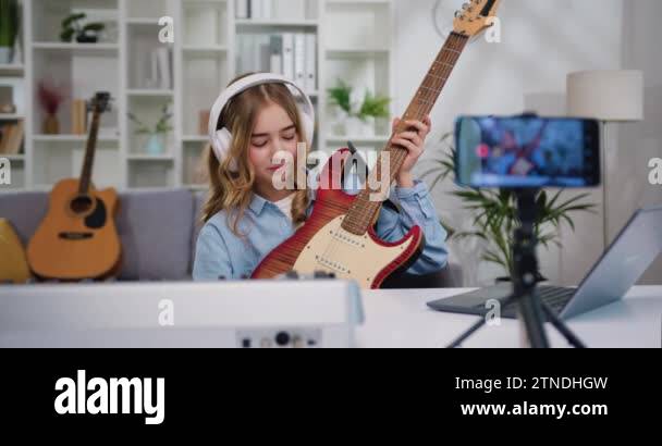 Beautiful preteen female blogger recording video class tutorial for play electric guitar on ...