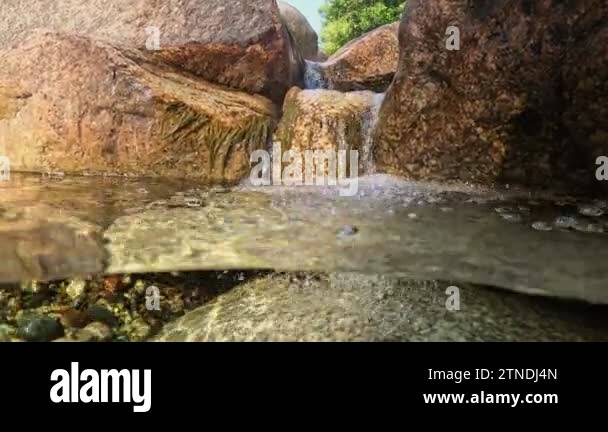 Stream with crystal clear water and bubbles. Water flows between the ...