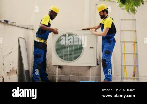 Teamworking competent mechanic opening up rusty out of service HVAC ...