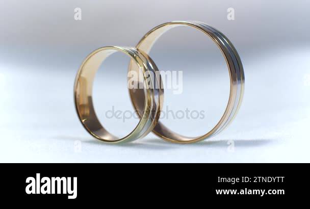 Two gold wedding rings lying on white-gray surface shining with light ...