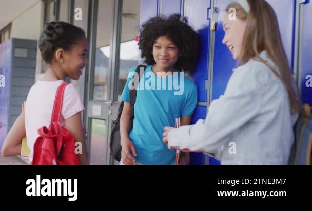 Video of three diverse, happy schoolgirls talking by lockers in school ...