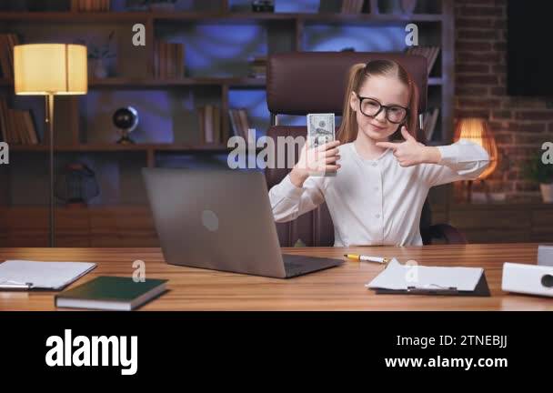 Little business lady sitting in front of laptop at long wooden desktop ...
