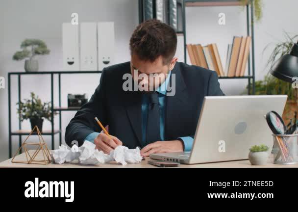 Angry furious young man working at office throwing crumpled paper ...