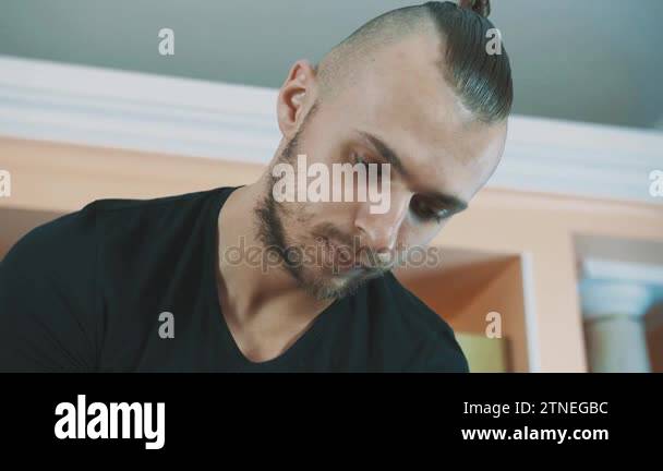 Confectioner muscular man squeezes whiped creme puffs in line onto cake ...