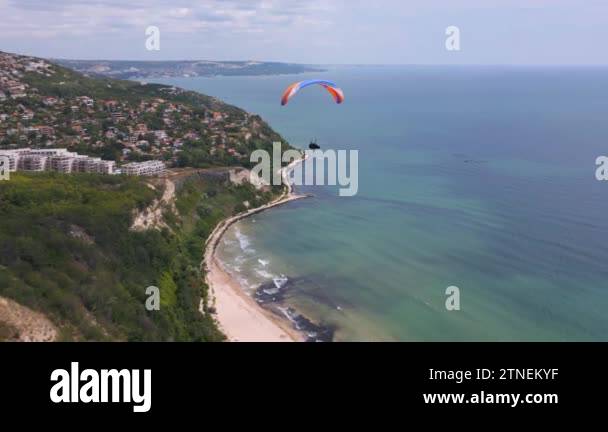 A paraglider soars over the sea and forest with a breathtaking view of ...