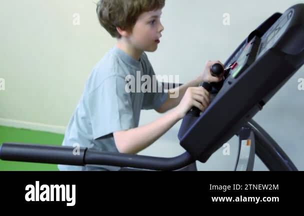 Little boy walks on treadmill and looks to panel with hands on ...