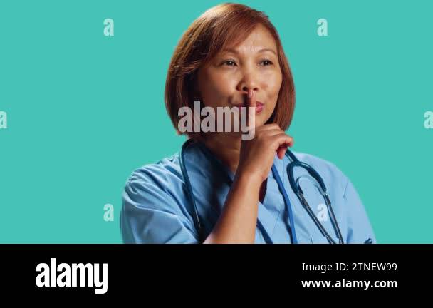 Close up shot of rigid strict BIPOC clinic manager shushing at camera ...