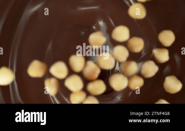 Super Slow Motion Shot of Peeled Hazelnuts Falling into Swirling Melted ...