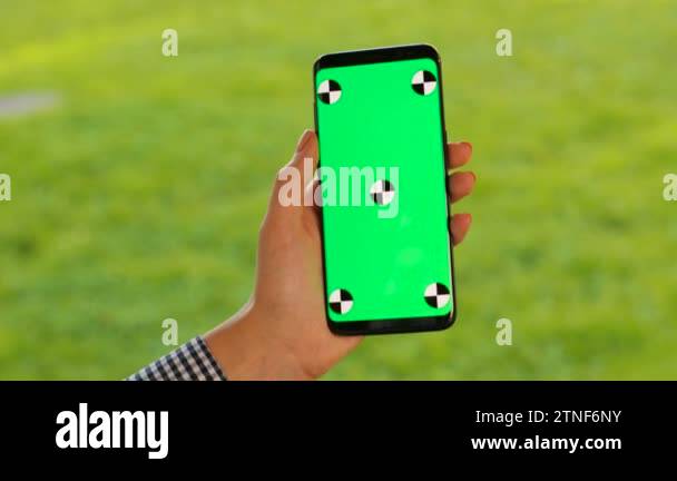 Female hand holding black smartphone with green screen on. Woman scrolling, tapping on ...
