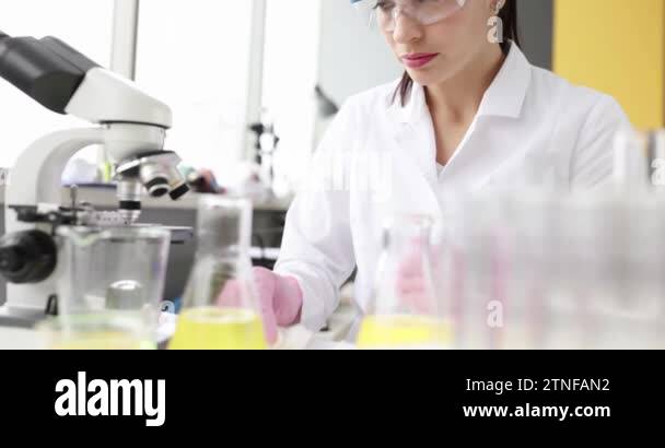 Young woman scientist wipes table and microscope with napkin ...