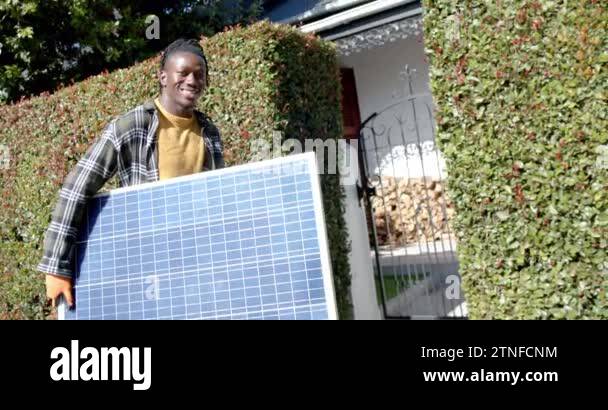 Portrait of happy african american man holding photovoltaic panel ...
