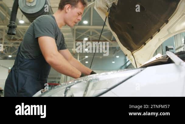 Professional talented mechanic concentarted on doing a car inspection ...