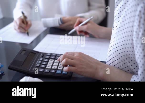 Two accountants use a calculator and laptop computer for counting taxes ...