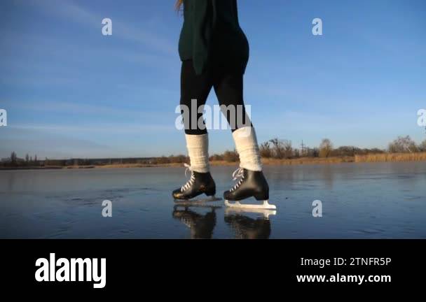 Legs of woman in figure skates sliding backwards on ice. Feet of girl ...
