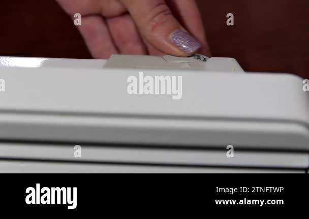 Close-up of a woman's hand switches the heater thermostat mode. A woman ...