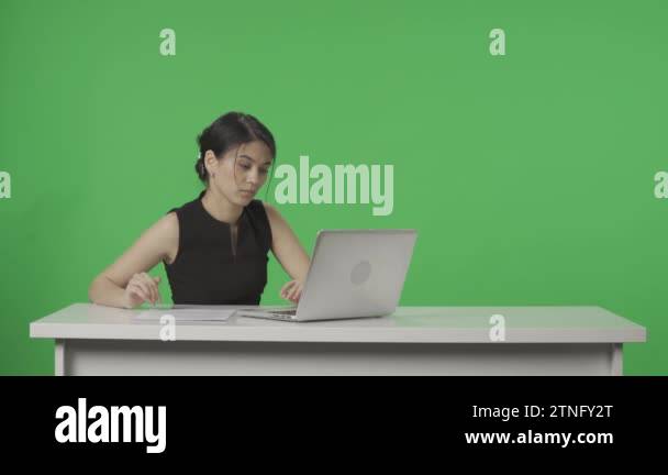 The TV presenter sits at a table in the studio against the background ...