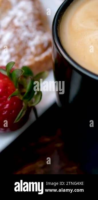 big black cup with coffee spoon stirring foam strawberry croissant on ...