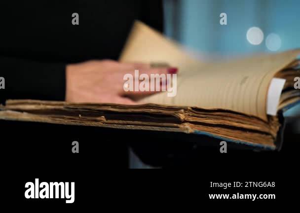 A woman reads historical documents from an old book. An archivist or ...