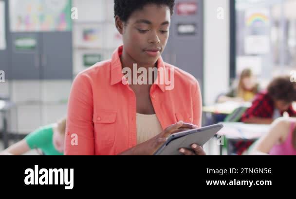 Portrait of diverse female teacher and schoolchildren at desks in ...