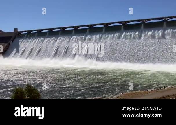 Tracking shot of the full length of Grand Coulee Dam with water flowing ...