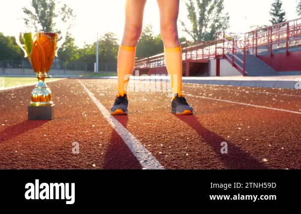 Sportsman legs on the running race at stadium with gold victory cup ...