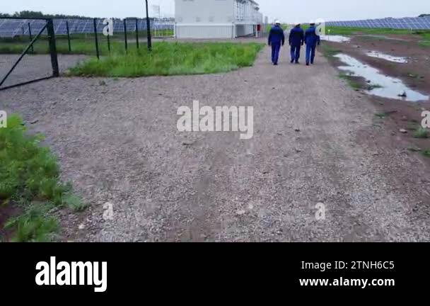 New solar farm under the blue sky. Workers in special outfit walk and ...