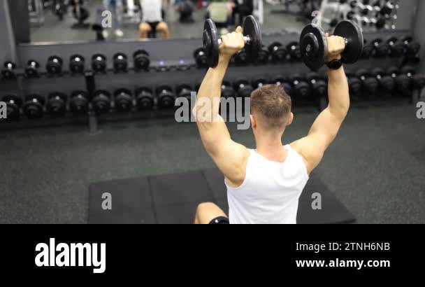 Man does lifts and holds heavy dumbbells in hands. Bodybuilder ...