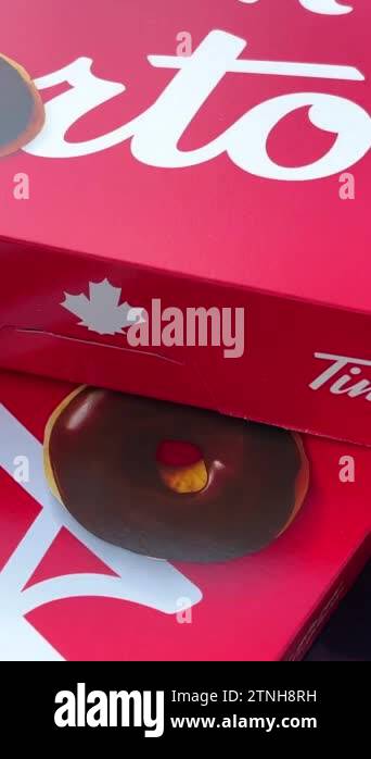 Large, open box of Tim Hortons donuts in contrasted light, with a ...