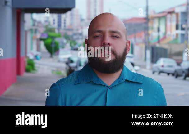 One serious South American man standing in urban street with stern ...