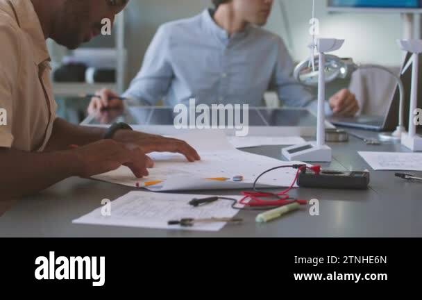 Biracial male electronics engineer drawing technical blueprint, sitting ...
