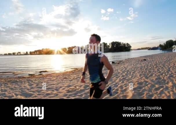 Strong male runner at the beach takes a break to get his breath back ...