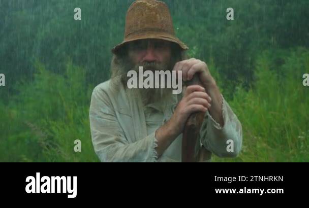 Close-up portrait of the old man with long beard, in old clothes is ...